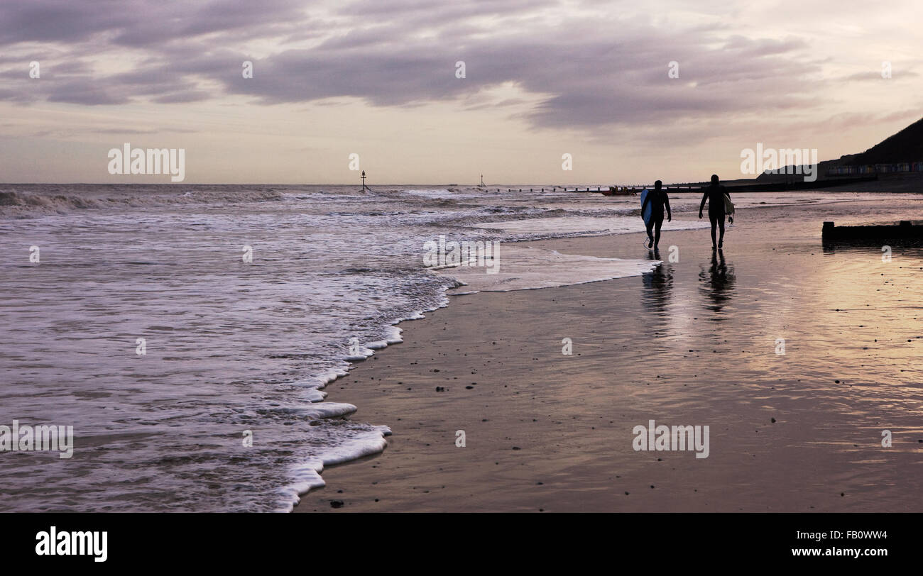 Two surfers are silhouetted as they walk out for a cold surf on a ...