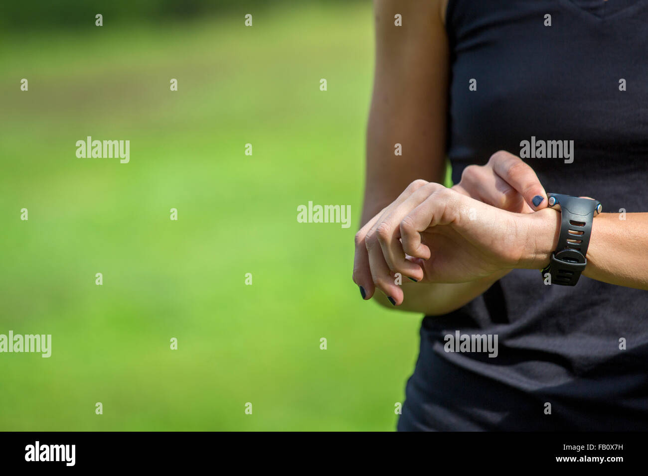 Young woman looking at watch during outdoors training Stock Photo - Alamy