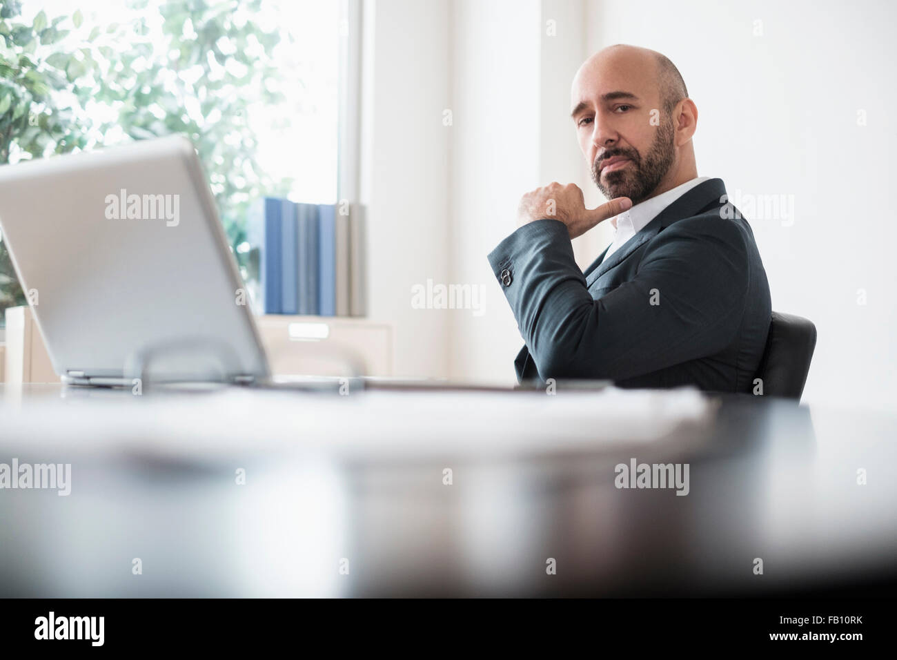 Serious businessman sitting at desk in office Stock Photo - Alamy