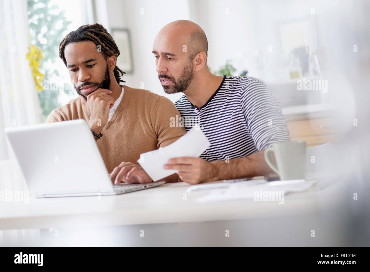 Two men working with laptop at table at home Stock Photo - Alamy
