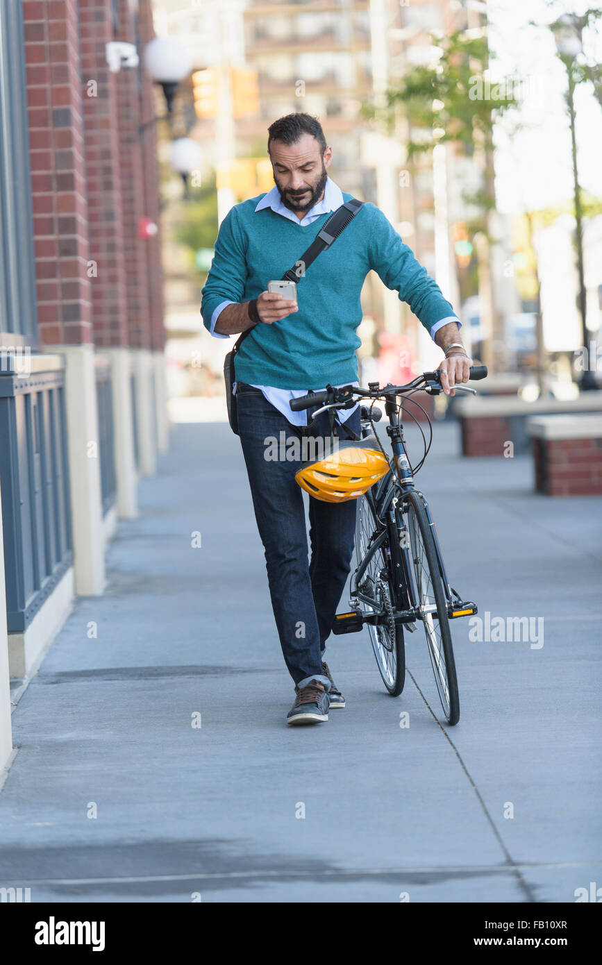 Man walking with bicycle using phone Stock Photo - Alamy
