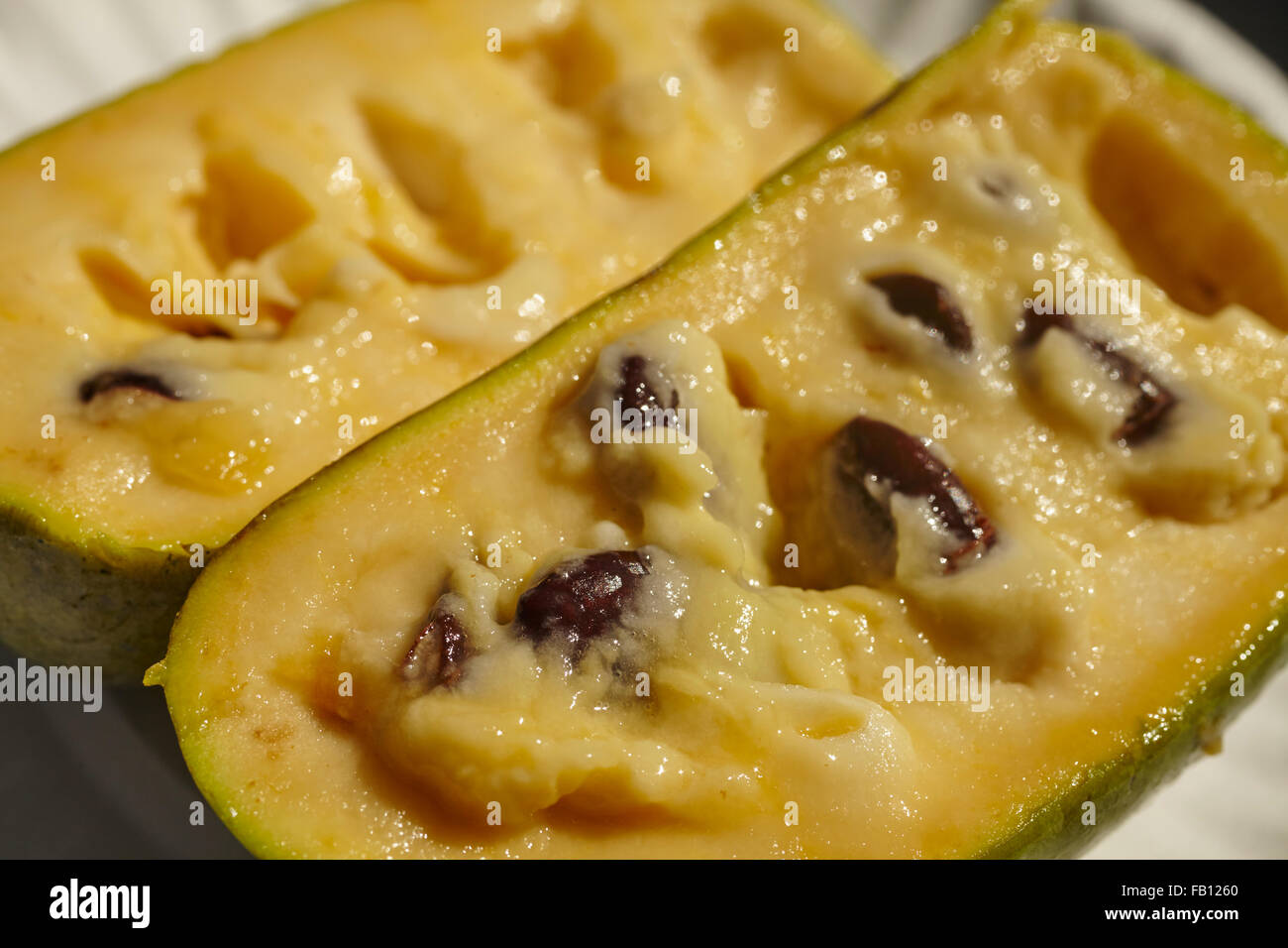 ripe, fresh American PawPaw, cut in half to show its flesh and seeds ...
