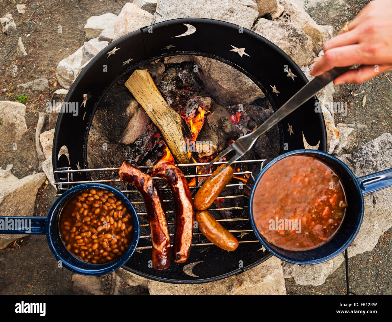 Man's hand cooking dinner on camp fire Stock Photo - Alamy
