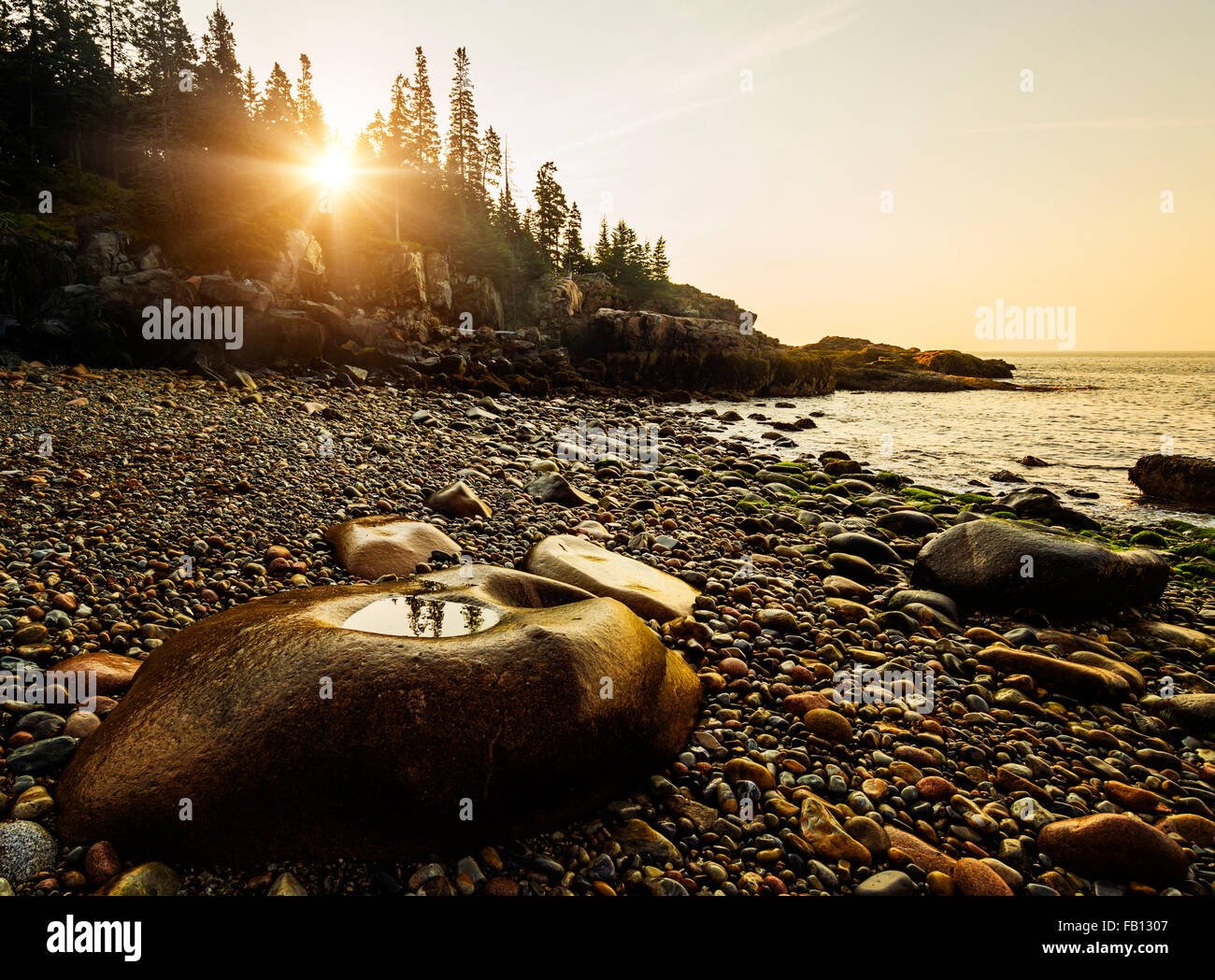 Rocks and pebbles on beach at sunrise Stock Photo - Alamy