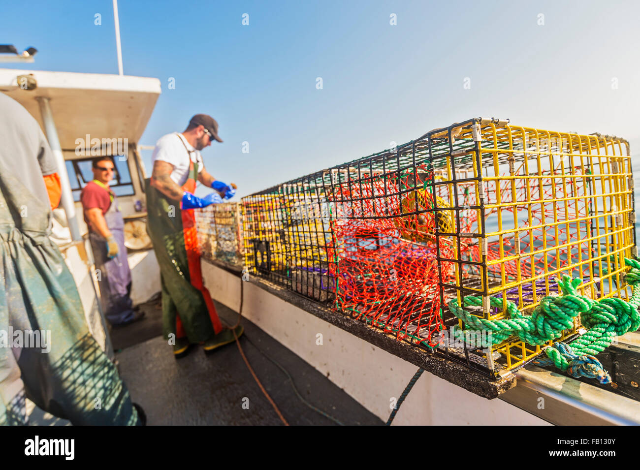 Three fishermen working on boat Stock Photo - Alamy