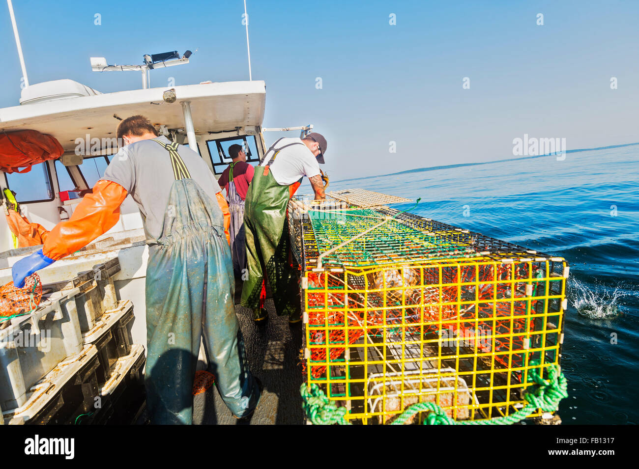 Three fishermen working on boat Stock Photo - Alamy
