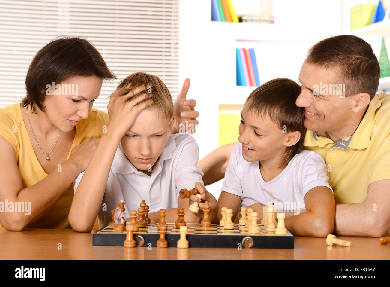 family playing chess sitting at table Stock Photo - Alamy