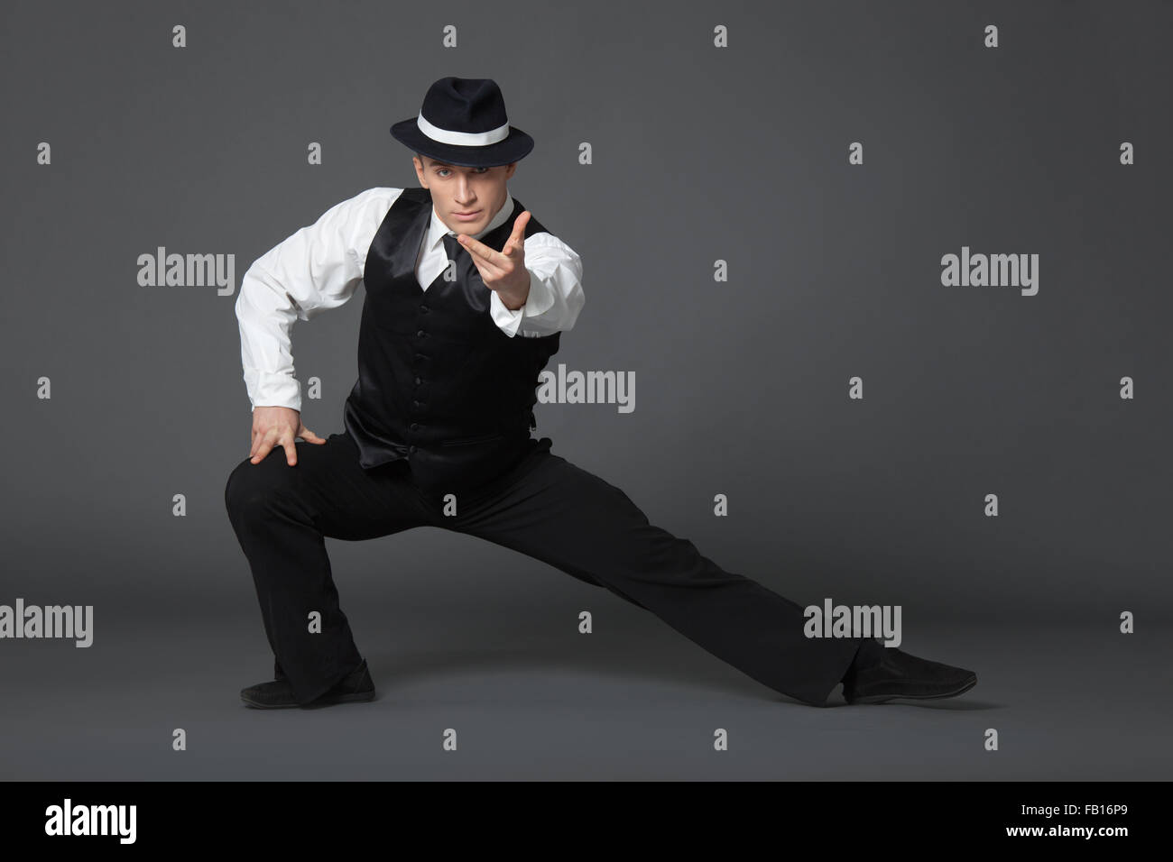 Young male professional dancer dancing in studio isolated on gray ...