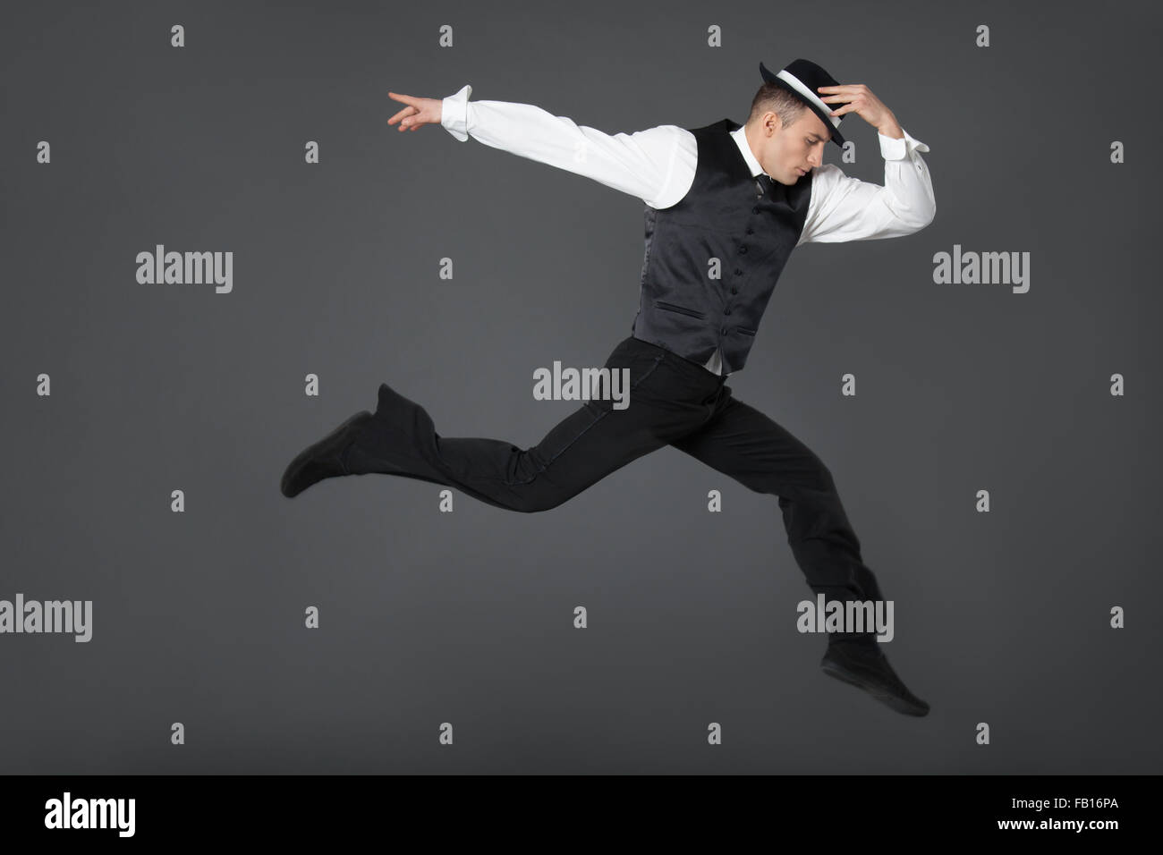Young male professional dancer dancing in studio isolated on gray ...