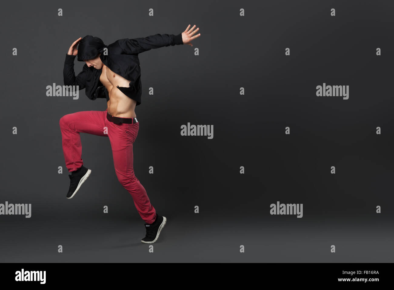 Young male professional dancer dancing in studio isolated on gray ...