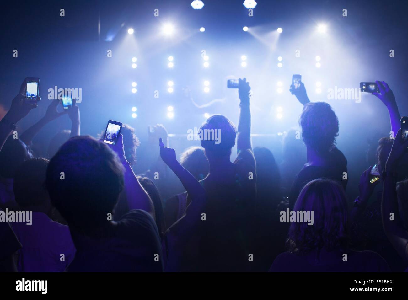 Group of friends watching and taking photograph of performer in club ...