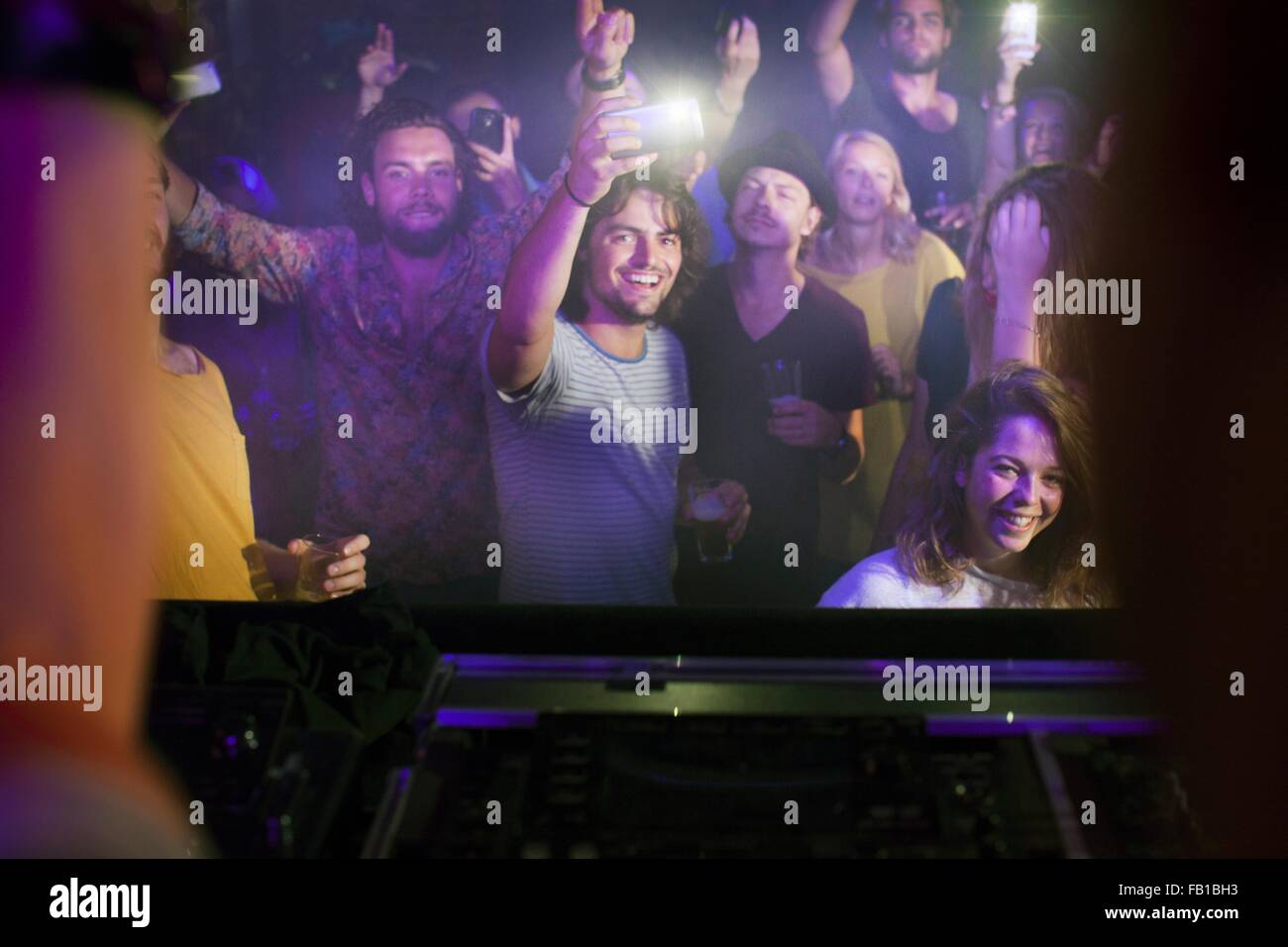 Group of friends watching and taking photograph of performer in club ...