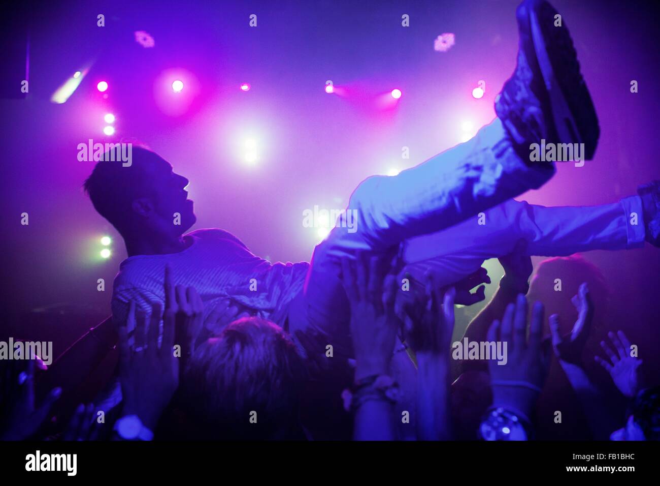 Group of people lifting man in club Stock Photo - Alamy