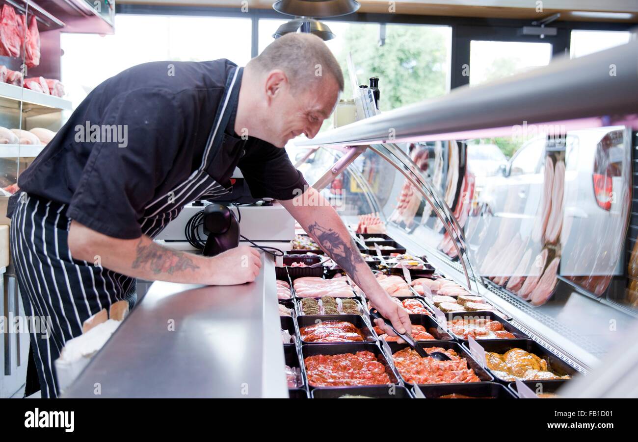 Butcher serving fresh food from refrigerator in butchers shop Stock ...