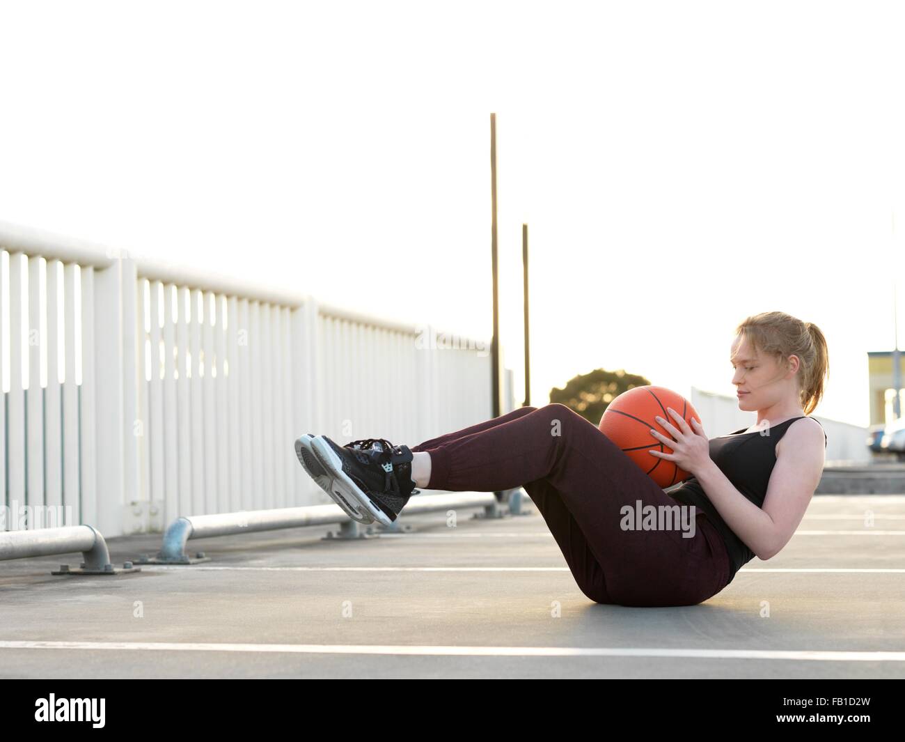 Young female basketball player doing sit-ups in parking lot Stock Photo ...
