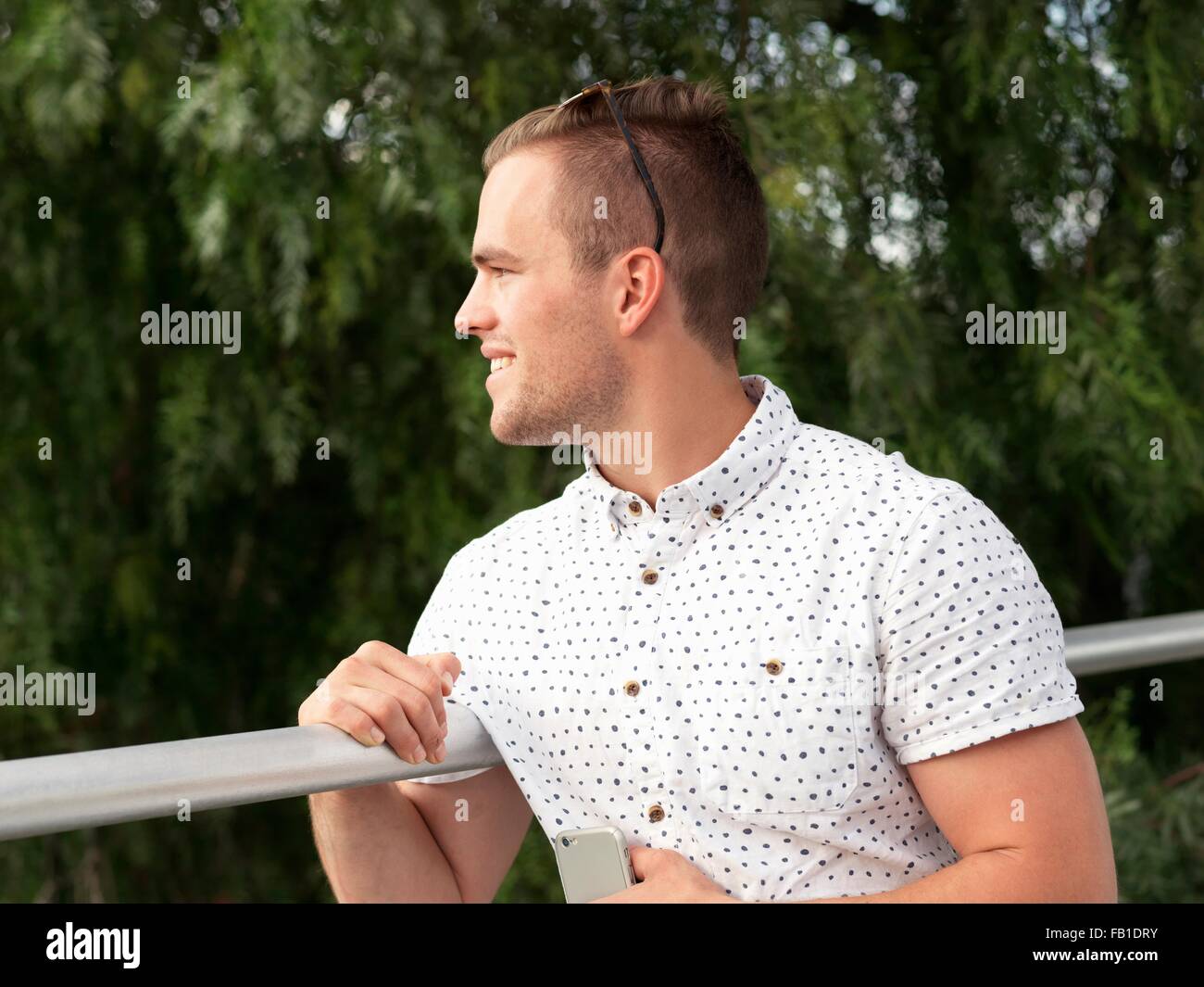 Young man, outdoors, leaning on railings, looking away Stock Photo - Alamy