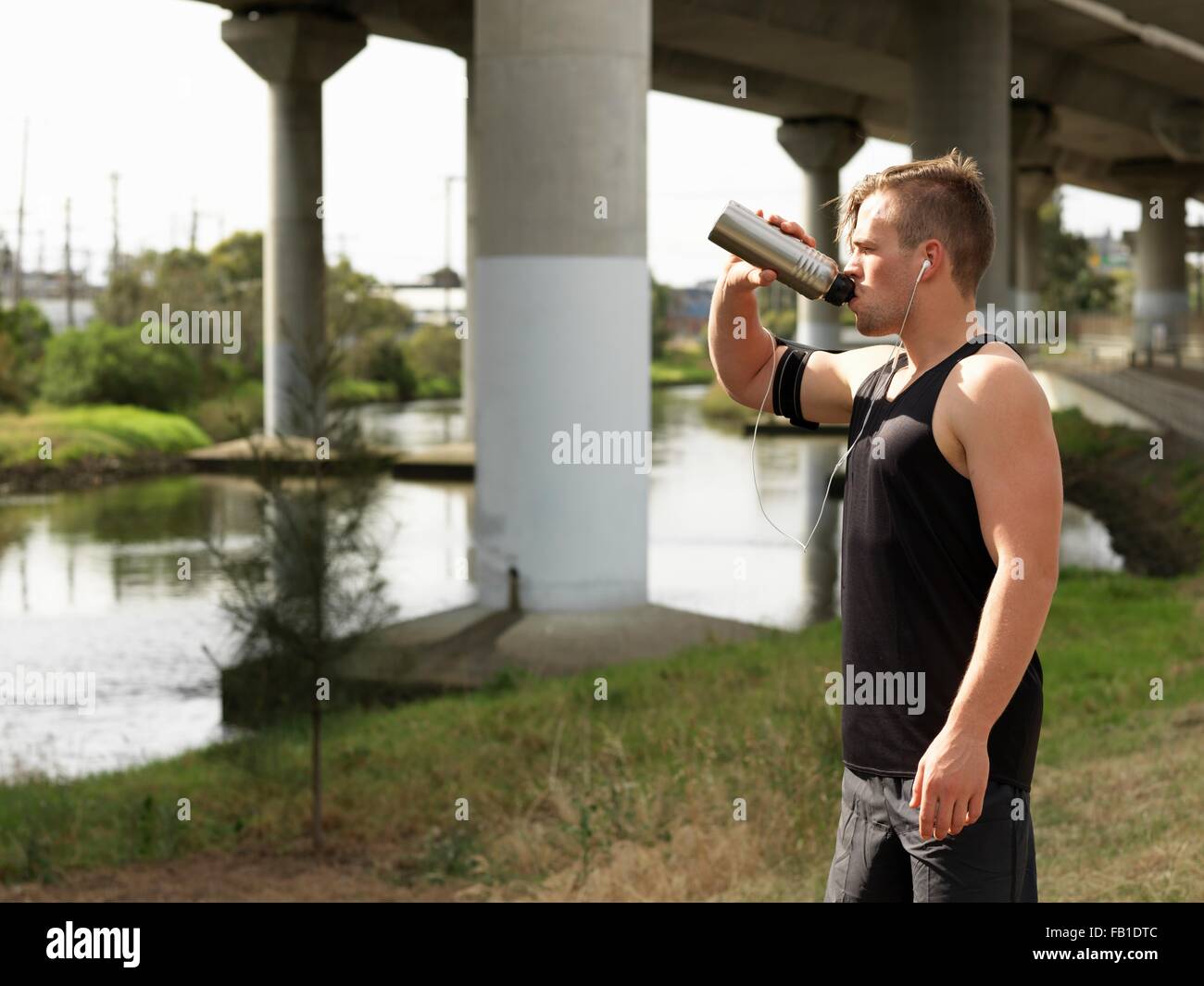 Young man beside river, drinking from water bottle Stock Photo - Alamy