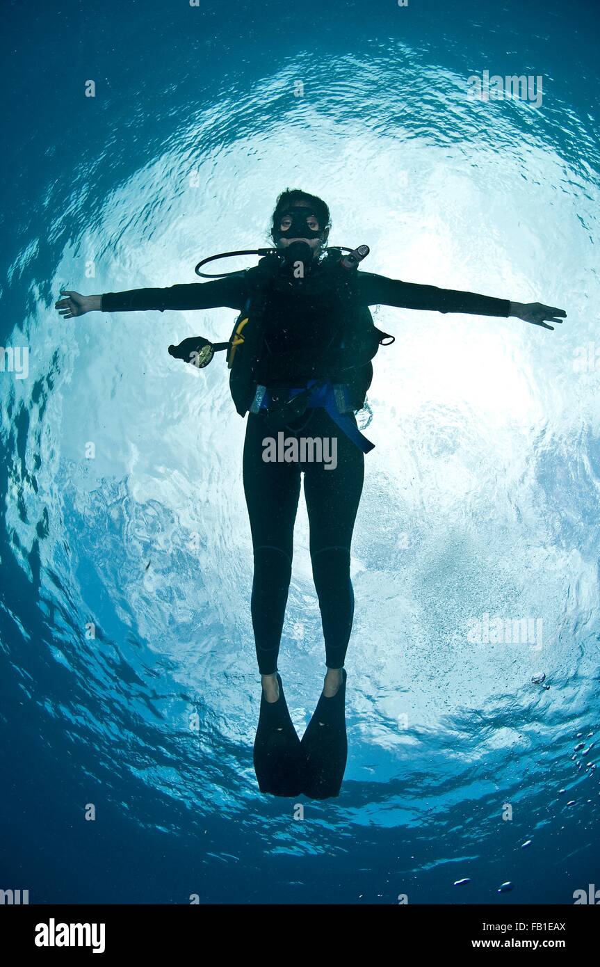 Full length view scuba diver arms open floating water surface camera ...