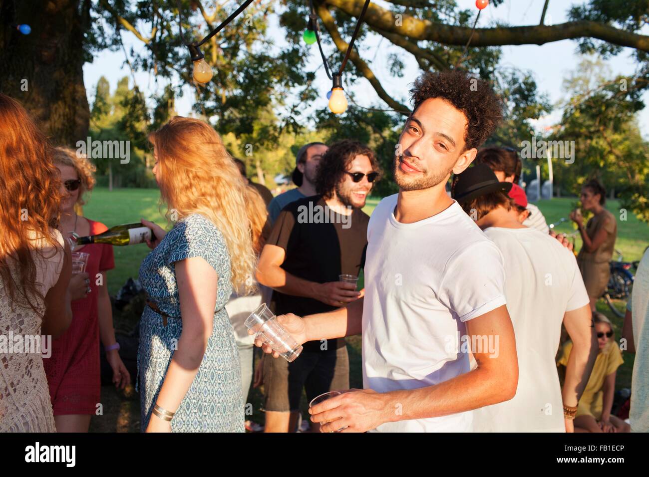 Portrait of mid adult man at crowded sunset party in park Stock Photo ...