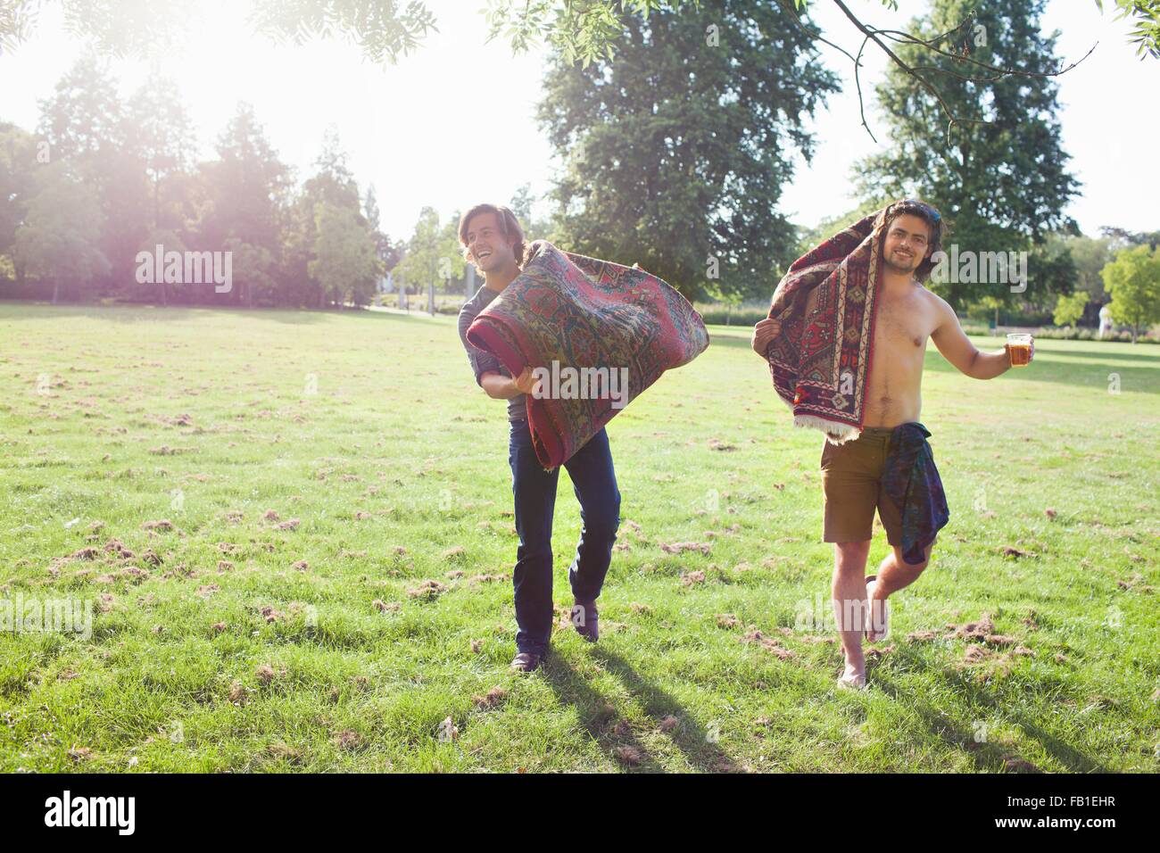 Two young men carrying rugs for sunset park party Stock Photo - Alamy