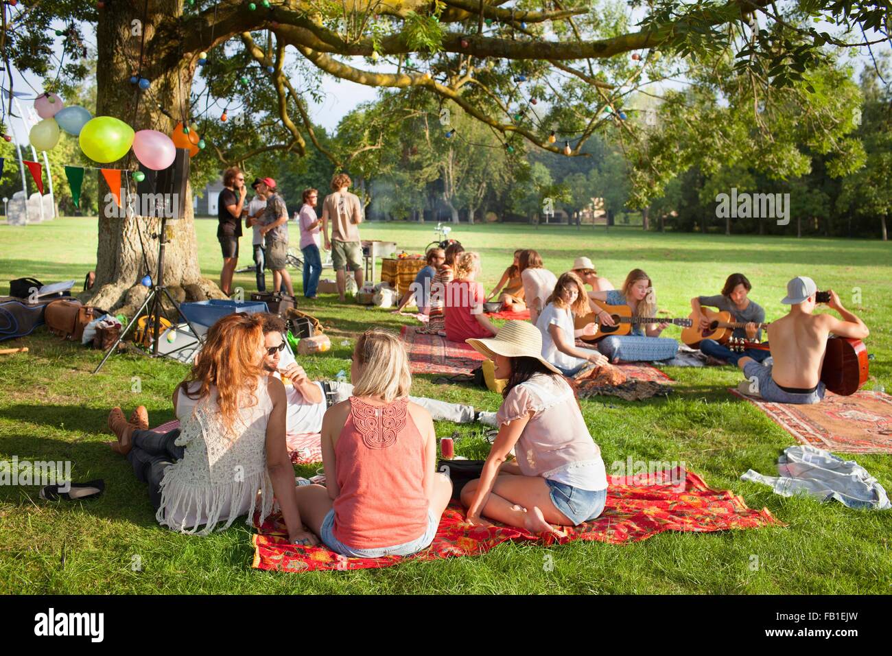 Woman playing guitar under tree hi-res stock photography and images - Alamy