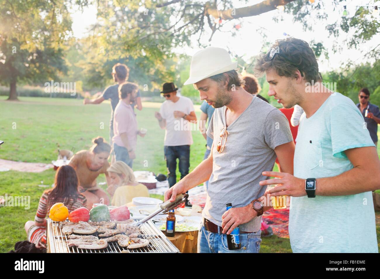 Young men barbecuing at group party in park Stock Photo - Alamy