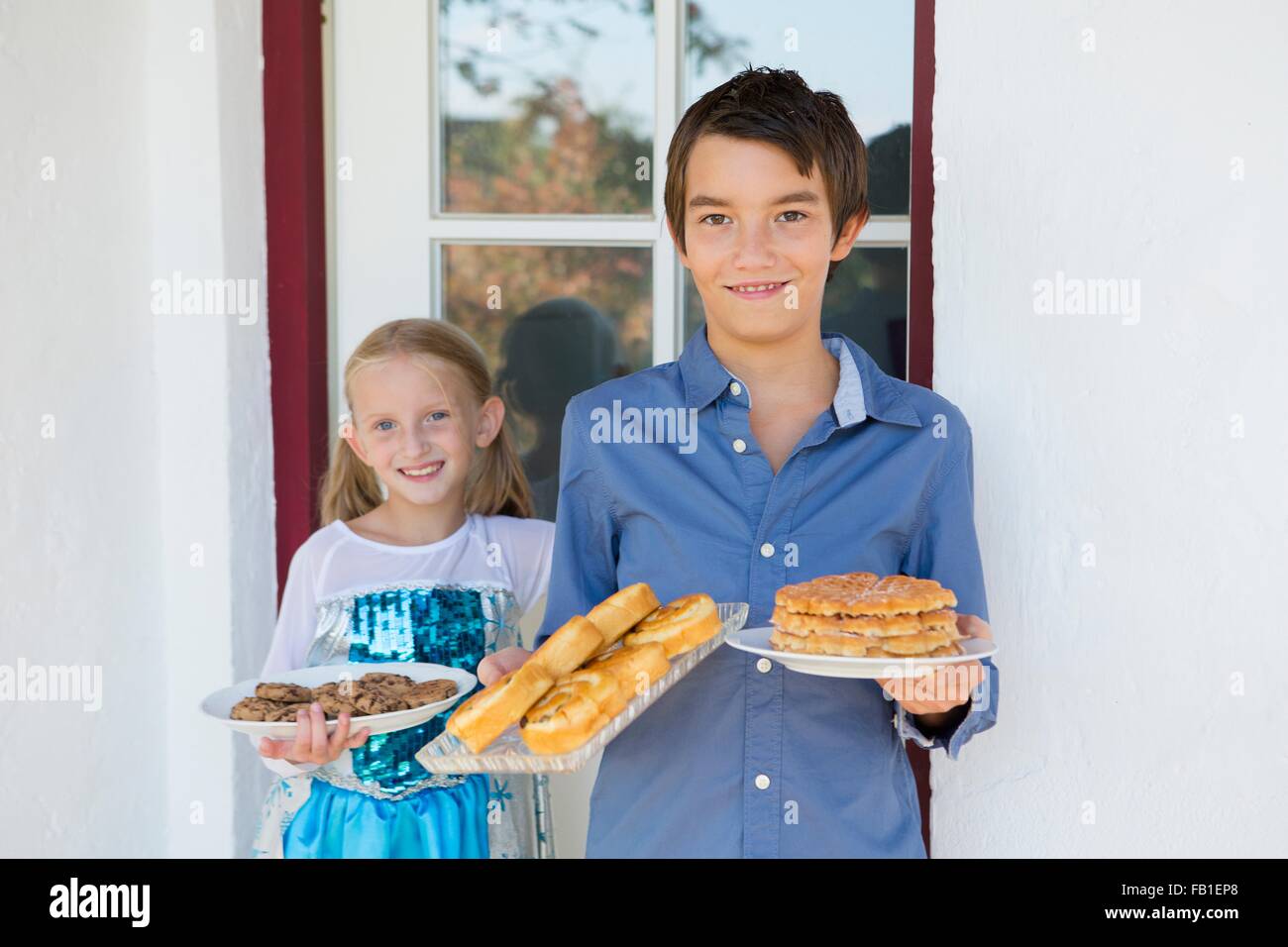 Portrait of teenage boy and sister carrying cakes on patio Stock Photo ...