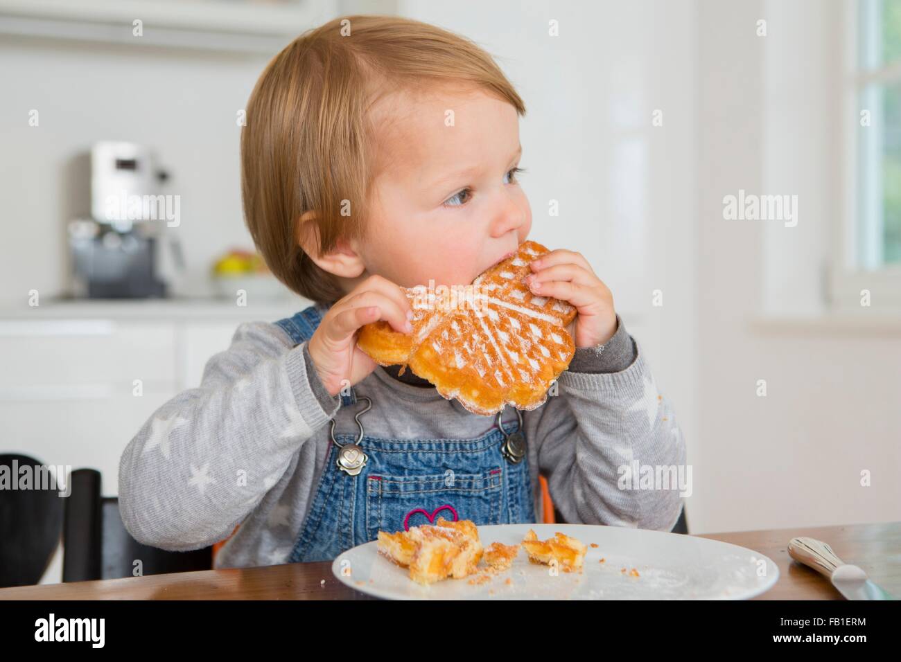 Cute female toddler eating cake at kitchen table Stock Photo - Alamy