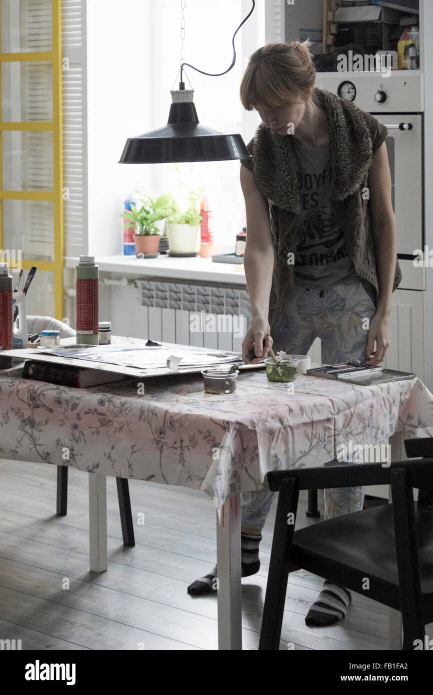 Female artist working at kitchen table Stock Photo - Alamy