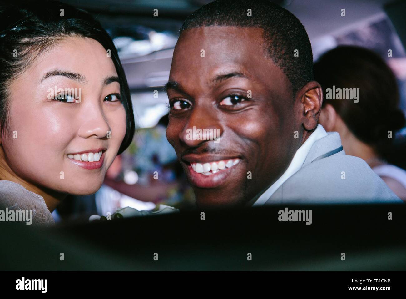 Portrait of couple looking over shoulder at camera smiling Stock Photo ...