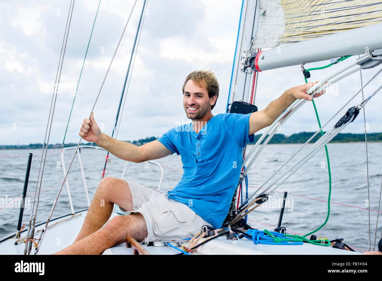 Young man sitting on sailboat looking at camera smiling Stock Photo - Alamy