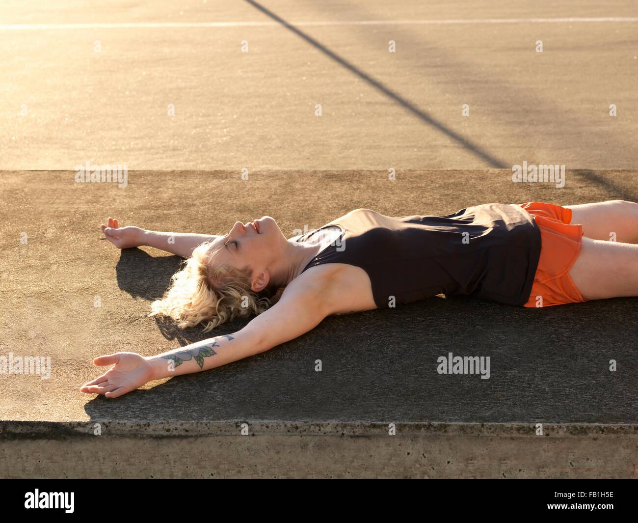 Exhausted young woman taking a training break in parking lot Stock ...