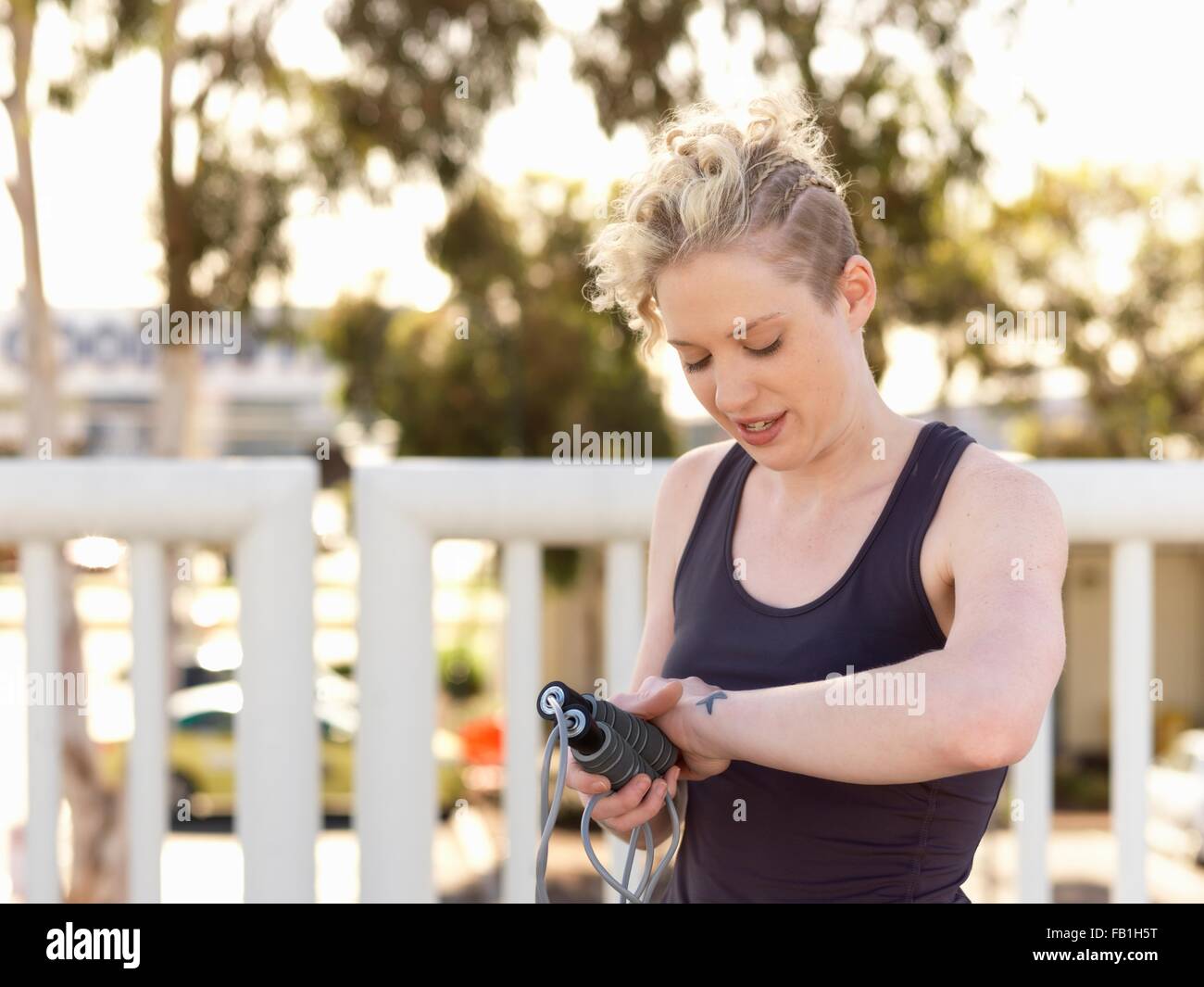 Young woman preparing skipping ropes for training on urban balcony ...