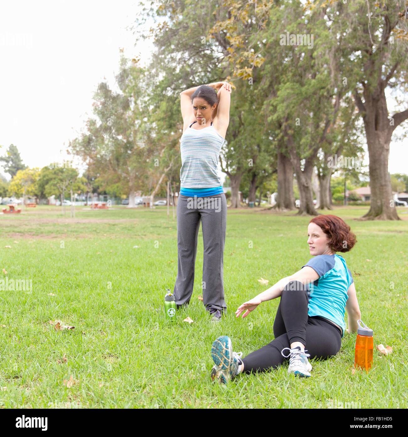 Young women wearing sports clothing on grass stretching Stock Photo - Alamy