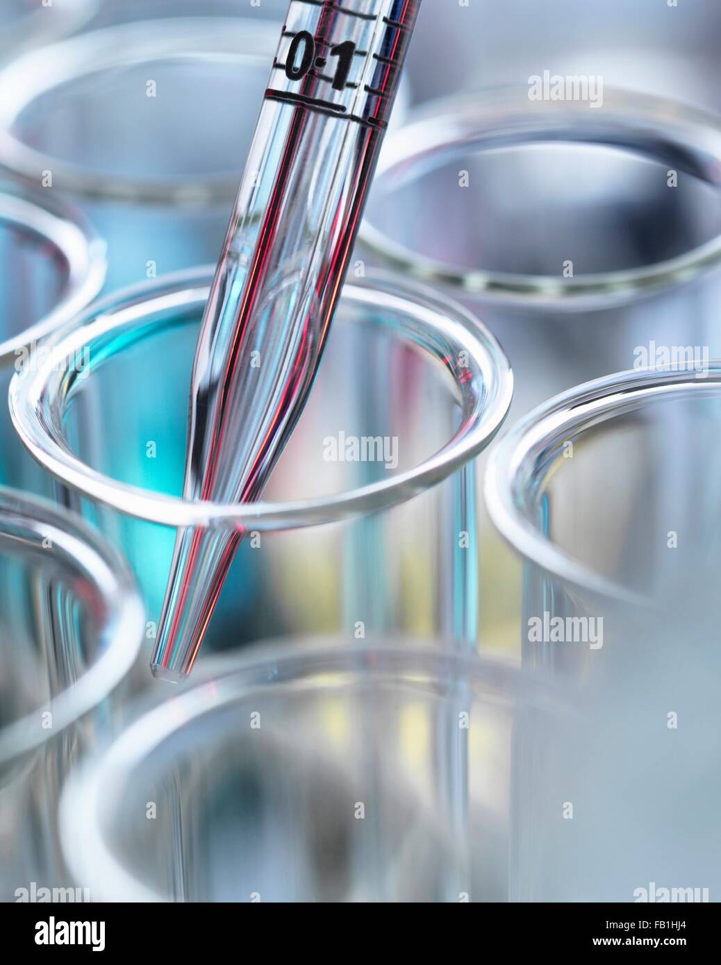 High angle cropped view of graduated pipette pipetting liquid into test ...