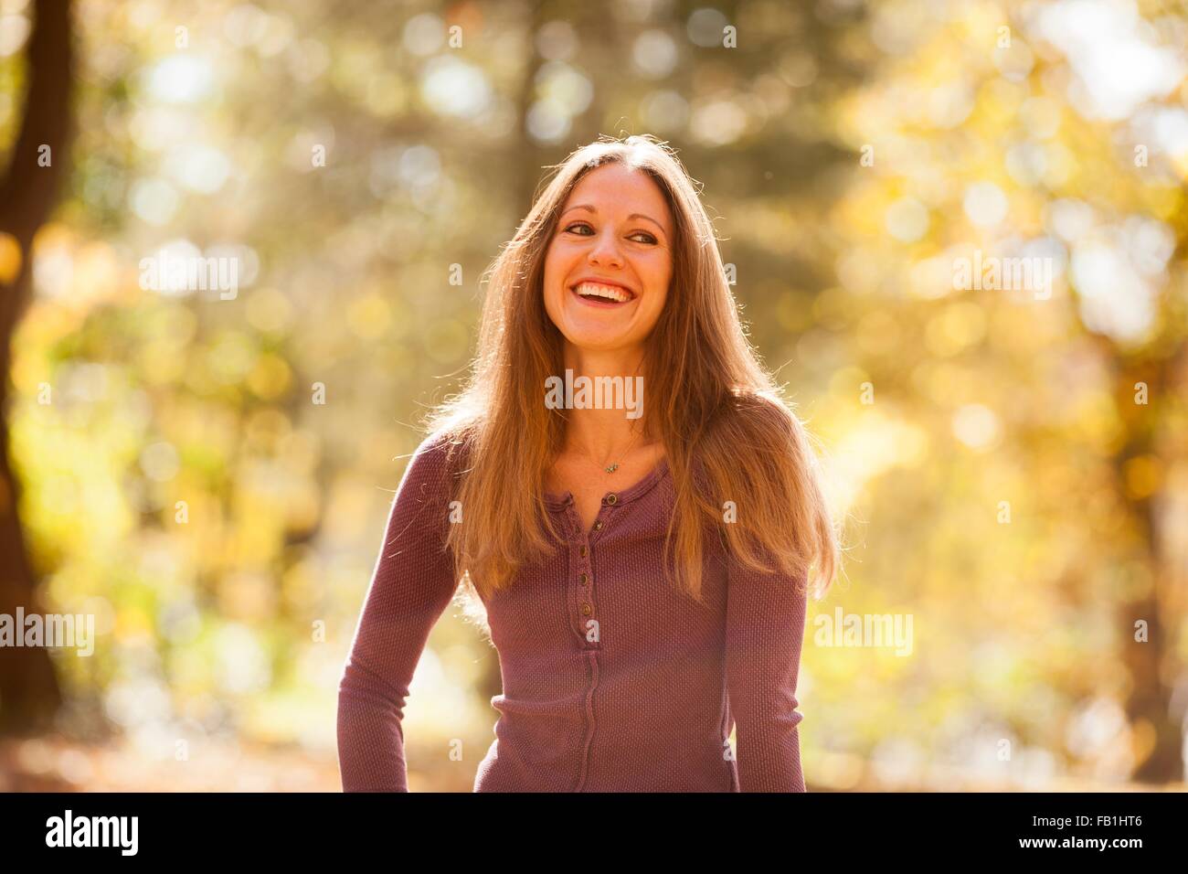 Sunlit portrait of long haired young man in autumn forest Stock Photo ...