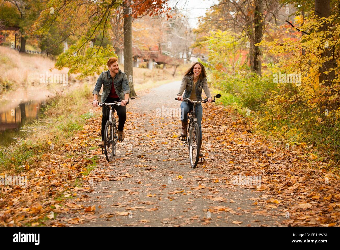 Happy young couple cycling on riverside in autumn Stock Photo - Alamy
