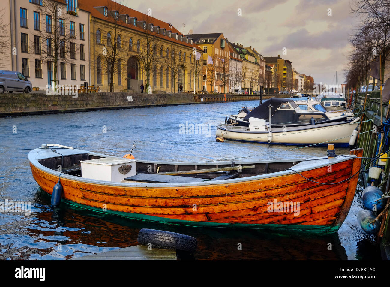 A small wooden boat floats peacefully on a waterfront canal in ...