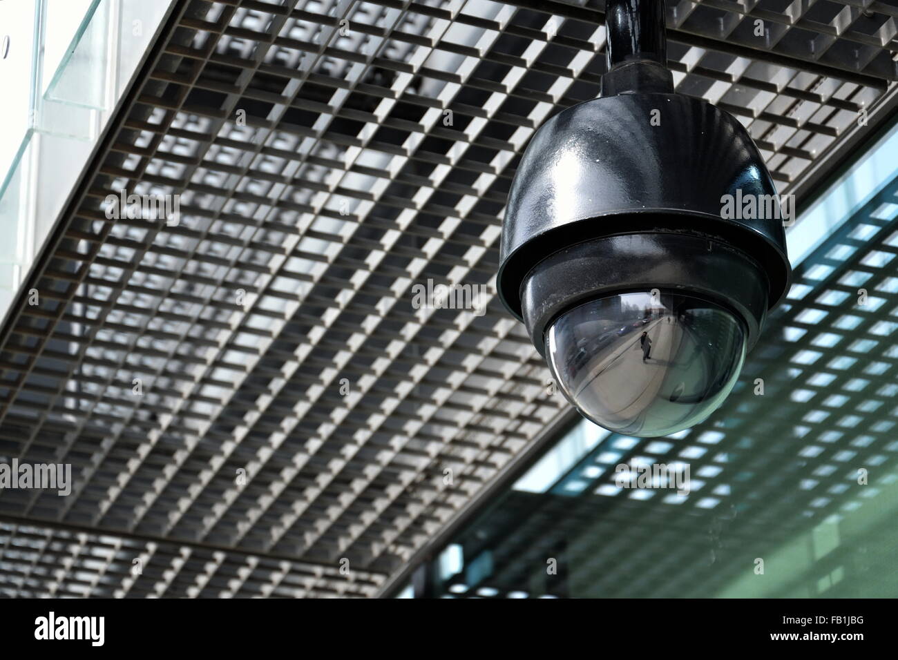 Security camera hanging down mounted on pole on the building facade ...