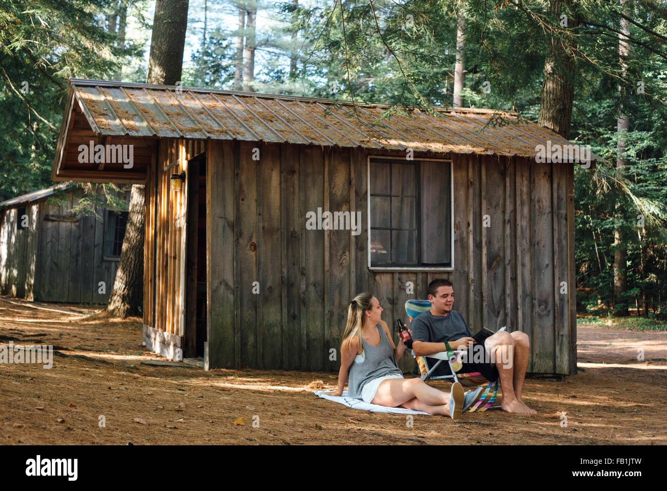Young couple relaxing outside hut in forest Stock Photo - Alamy