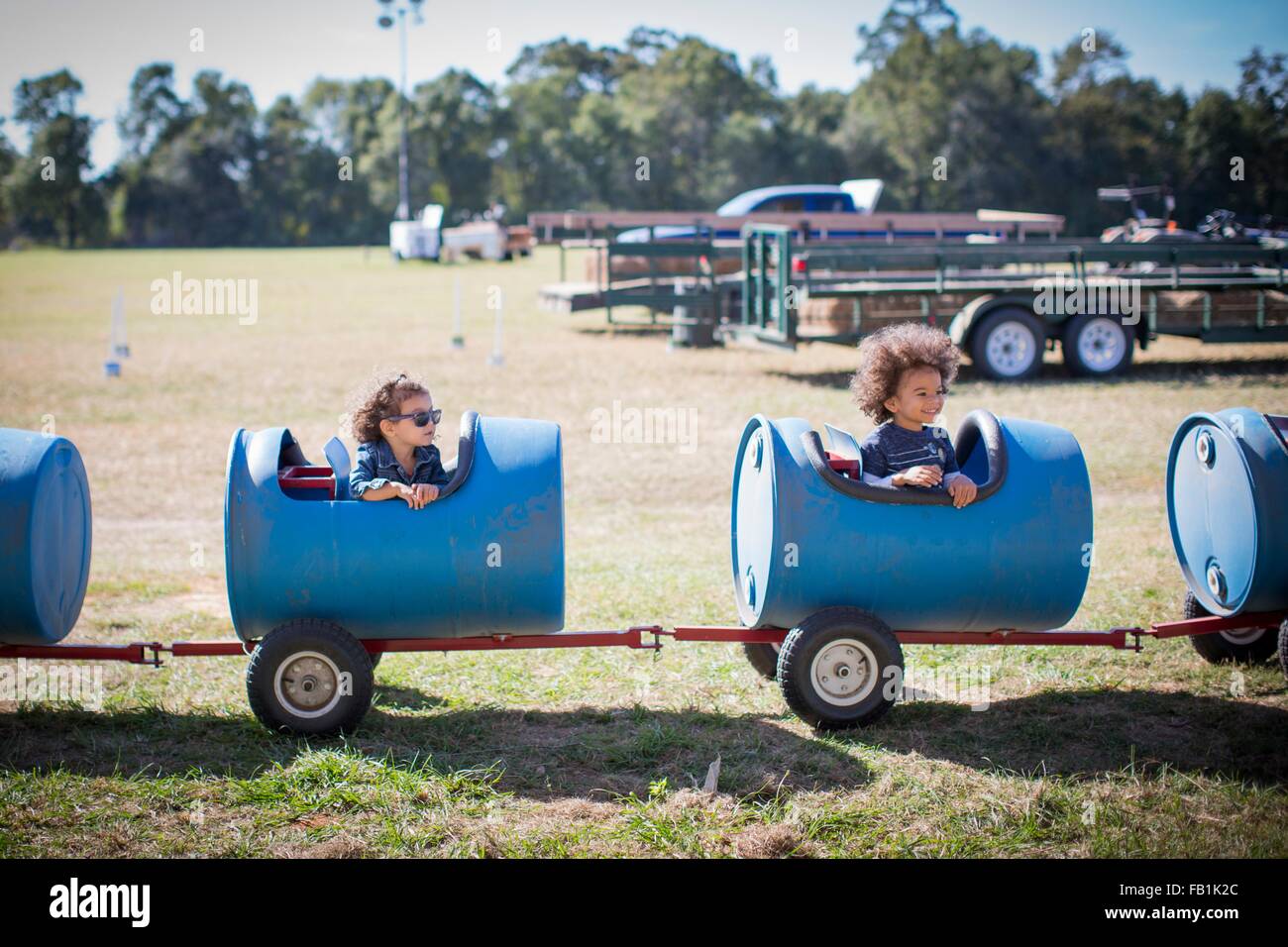 Children sitting in barrel cart looking away smiling Stock Photo - Alamy