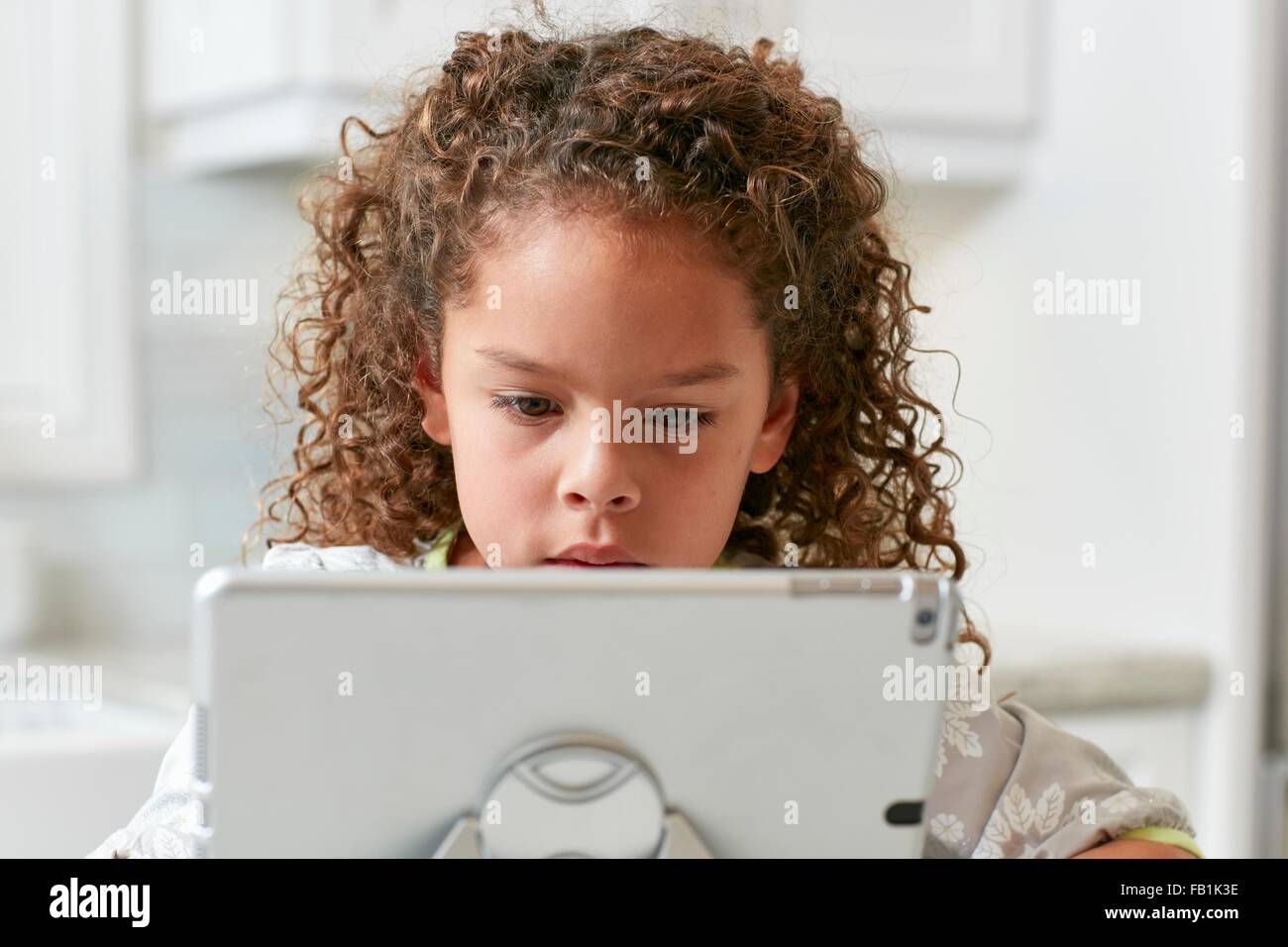 Girl using digital tablet looking down concentrating Stock Photo - Alamy