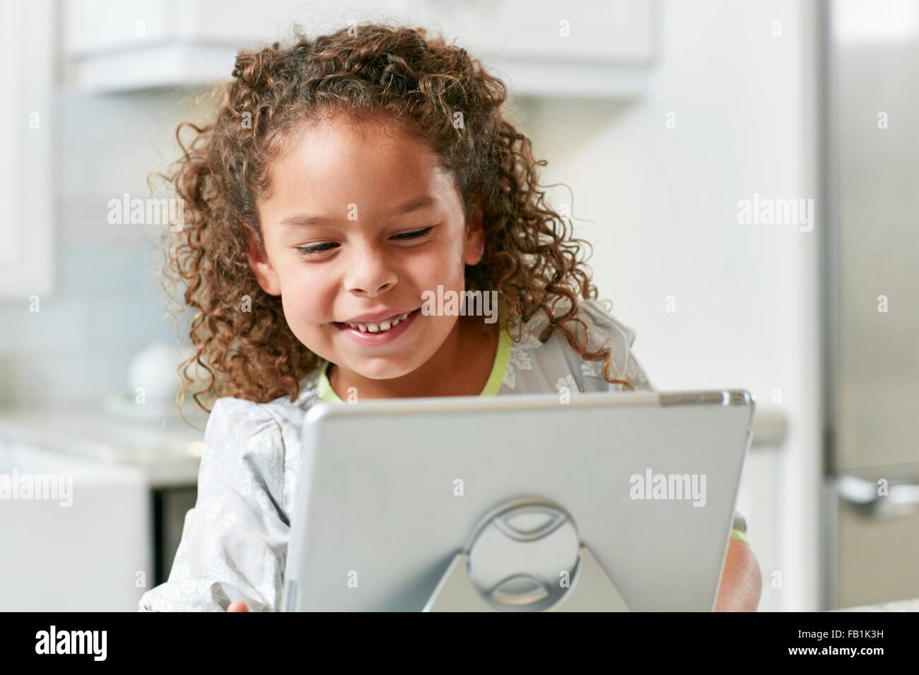 Girl using digital tablet looking down smiling Stock Photo - Alamy