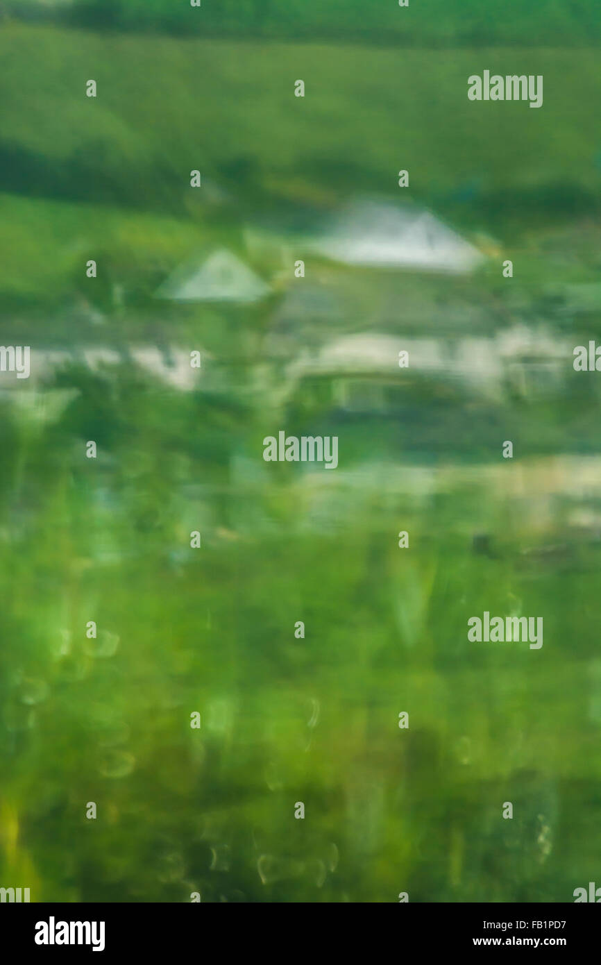Distorted window-reflected abstract image of a cluster of houses set in ...