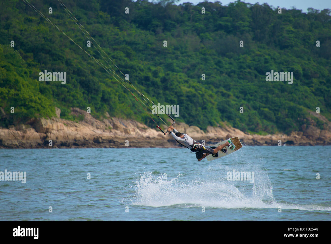 Male kite surfer jumping against wooded shore Stock Photo - Alamy