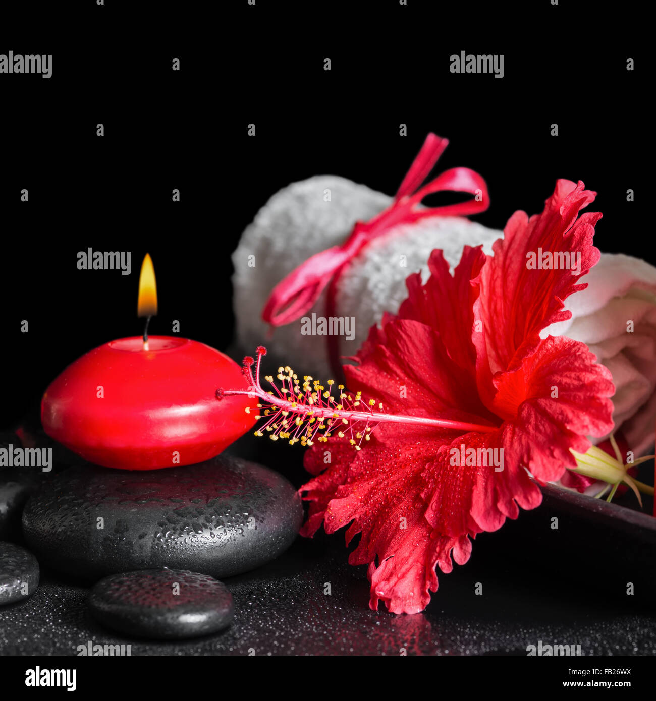 beautiful spa still life of red hibiscus flower with dew, candles and ...