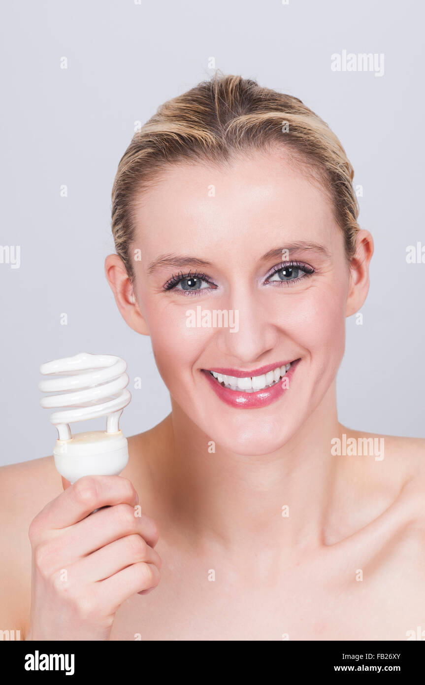 Happy young woman holding energy saving light bulb Stock Photo - Alamy