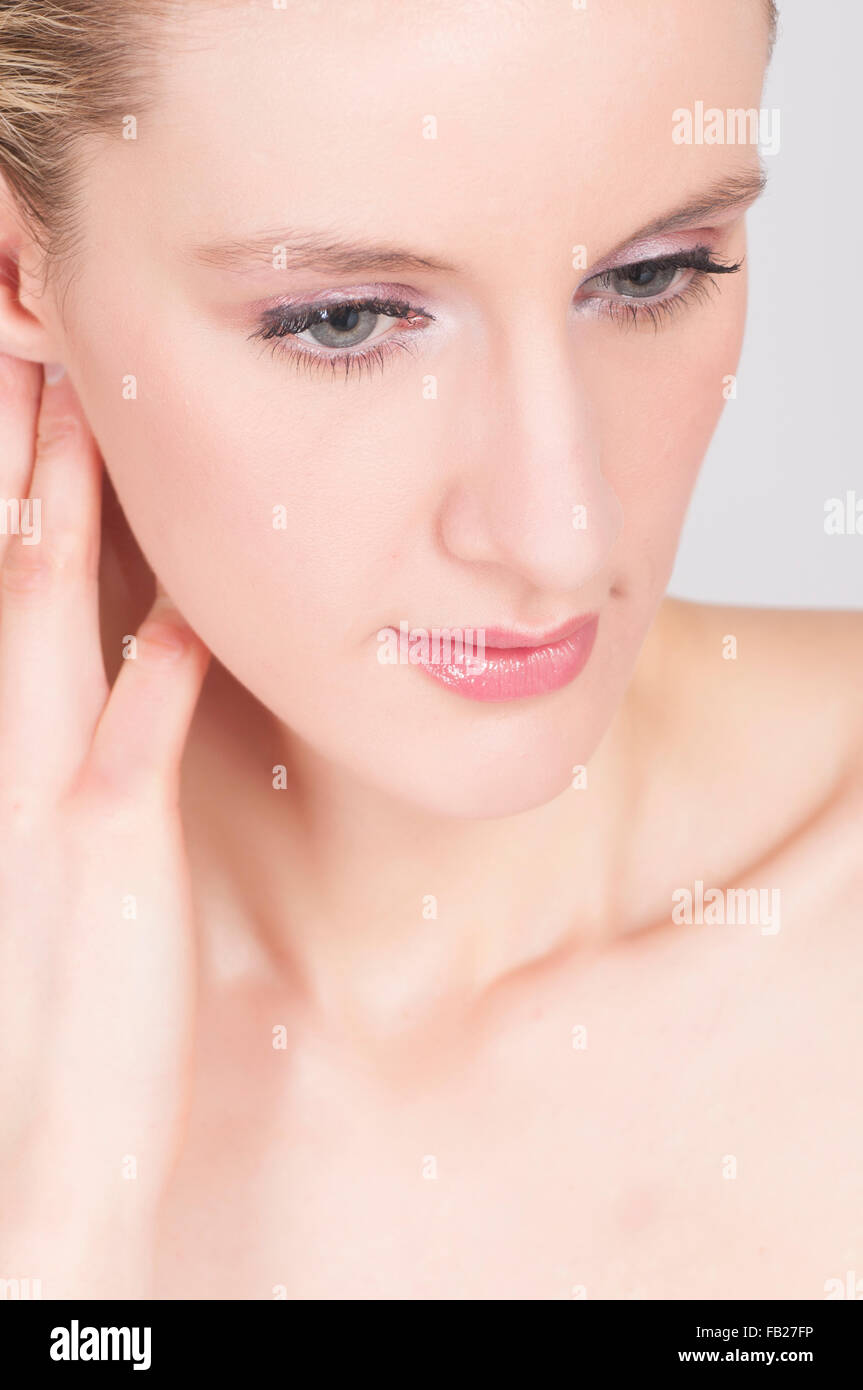 Pensive young woman hand touching neck looking away Stock Photo - Alamy