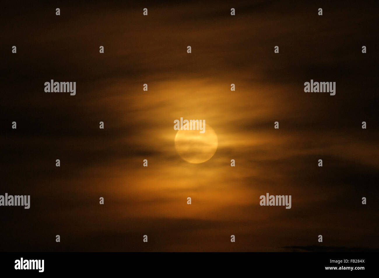 A full moon rises through the orange clouds of evening in Uganda ...
