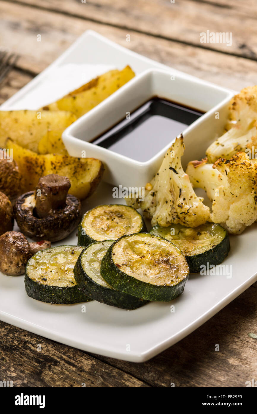 Roasted various vegetables with sauce on the wooden table. Vegetarian ...